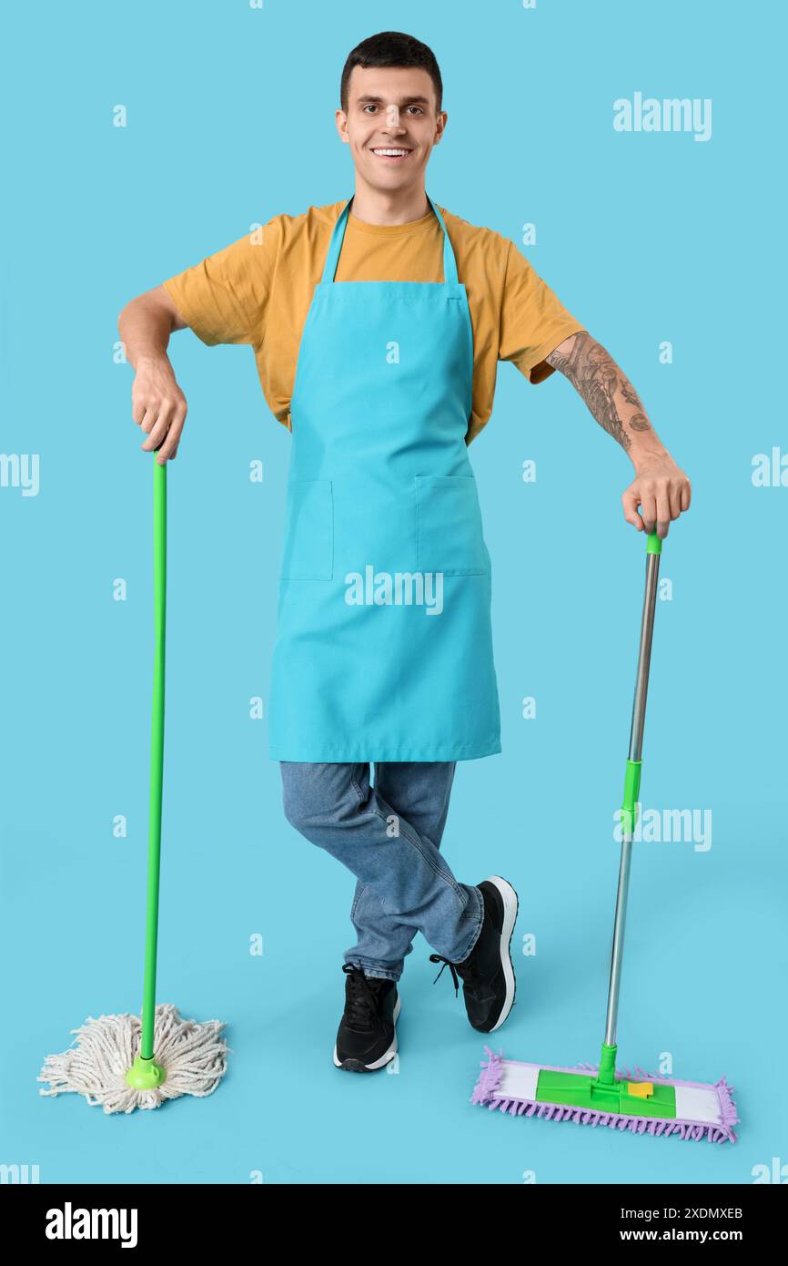 Male janitor with floor mops on blue background Stock Photo - Alamy