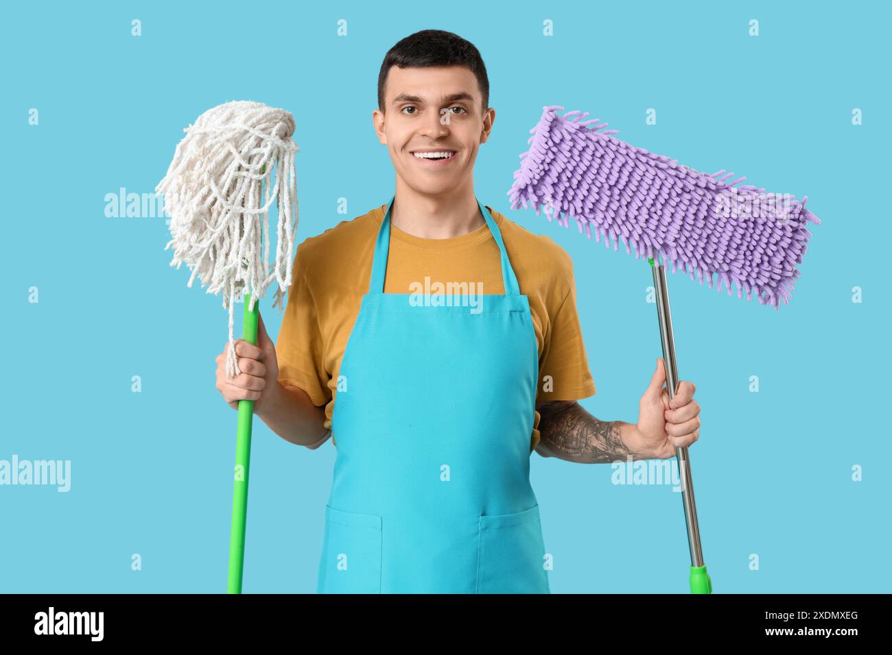 Male janitor with floor mops on blue background Stock Photo - Alamy