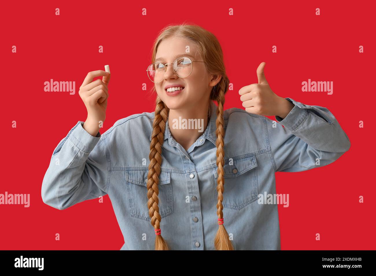 Teenage girl with chewing gum showing thumb-up on red background Stock ...