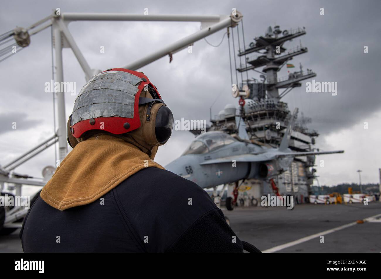 A Sailor guides a training F/A-18F during an aircraft recovery ...