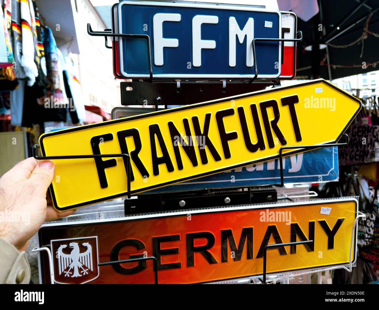 A hand picking a yellow Frankfurt sign from a display rack in a ...