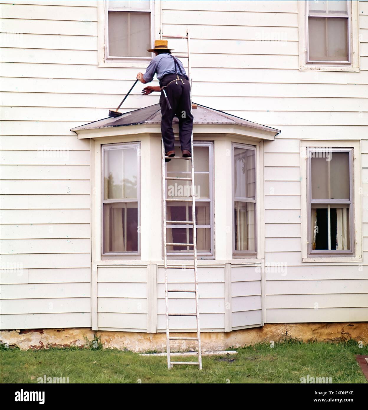 Amish man on step ladder, cleaning, painting house roof Stock Photo - Alamy