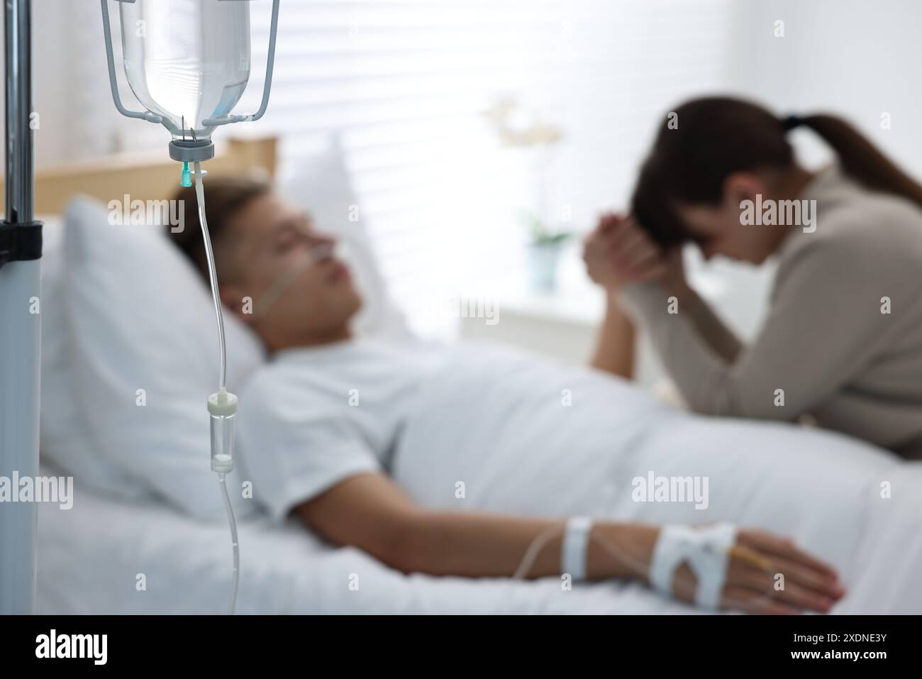 Coma patient. Sad young woman near her husband in hospital, selective ...