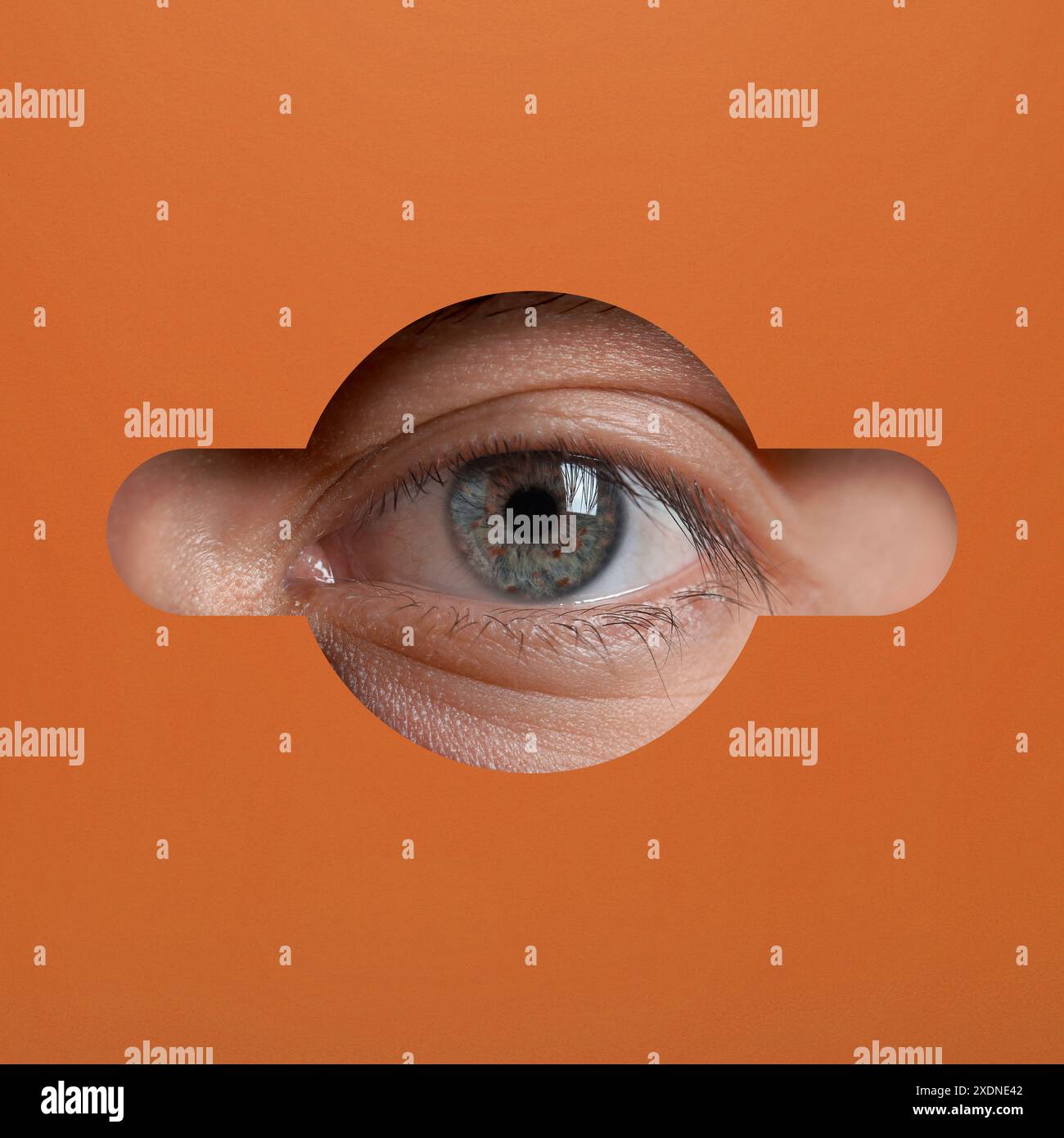 Man looking through keyhole in orange surface Stock Photo - Alamy