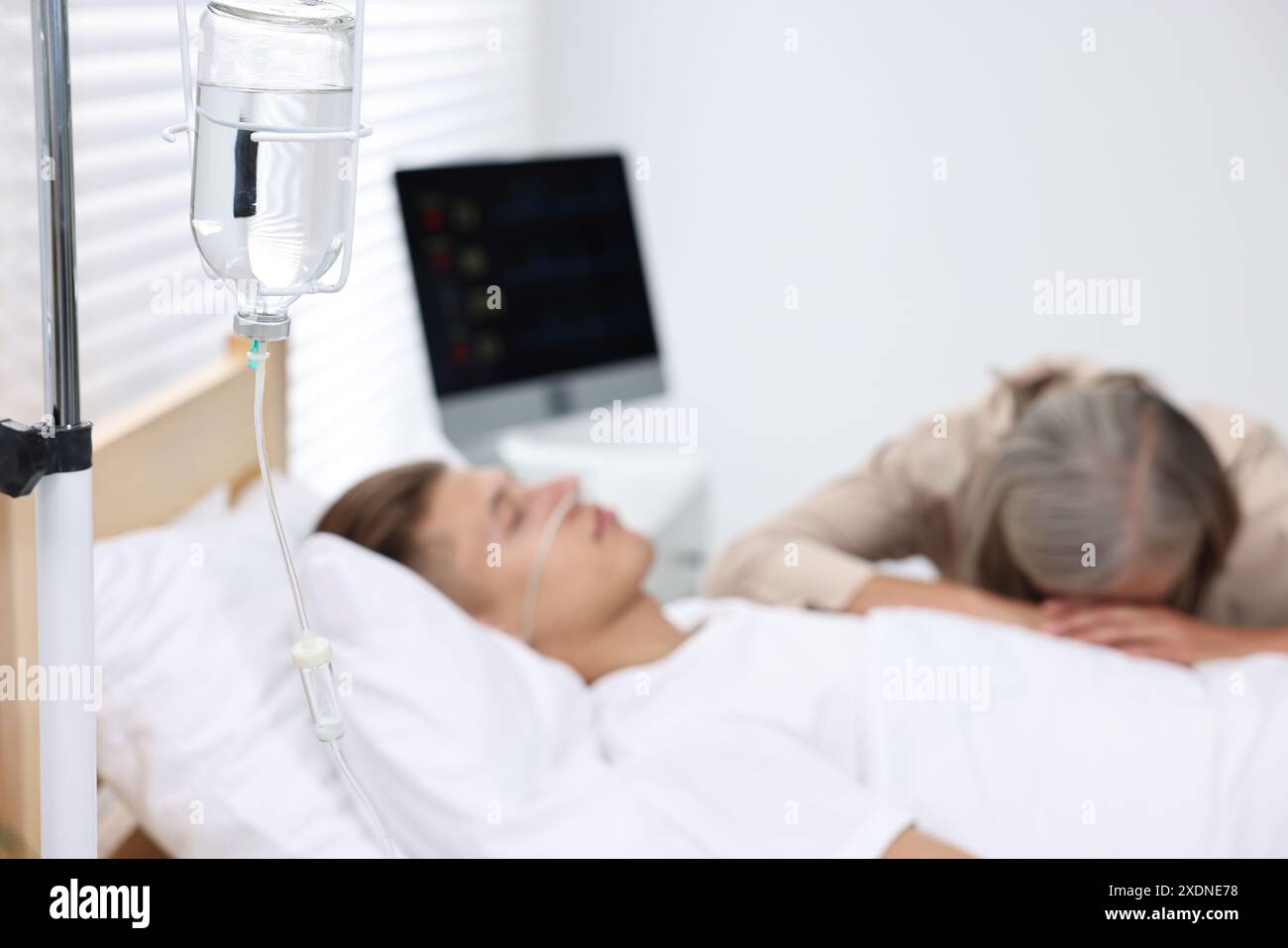 Coma patient. Sad mature woman near her unconscious son in hospital ...