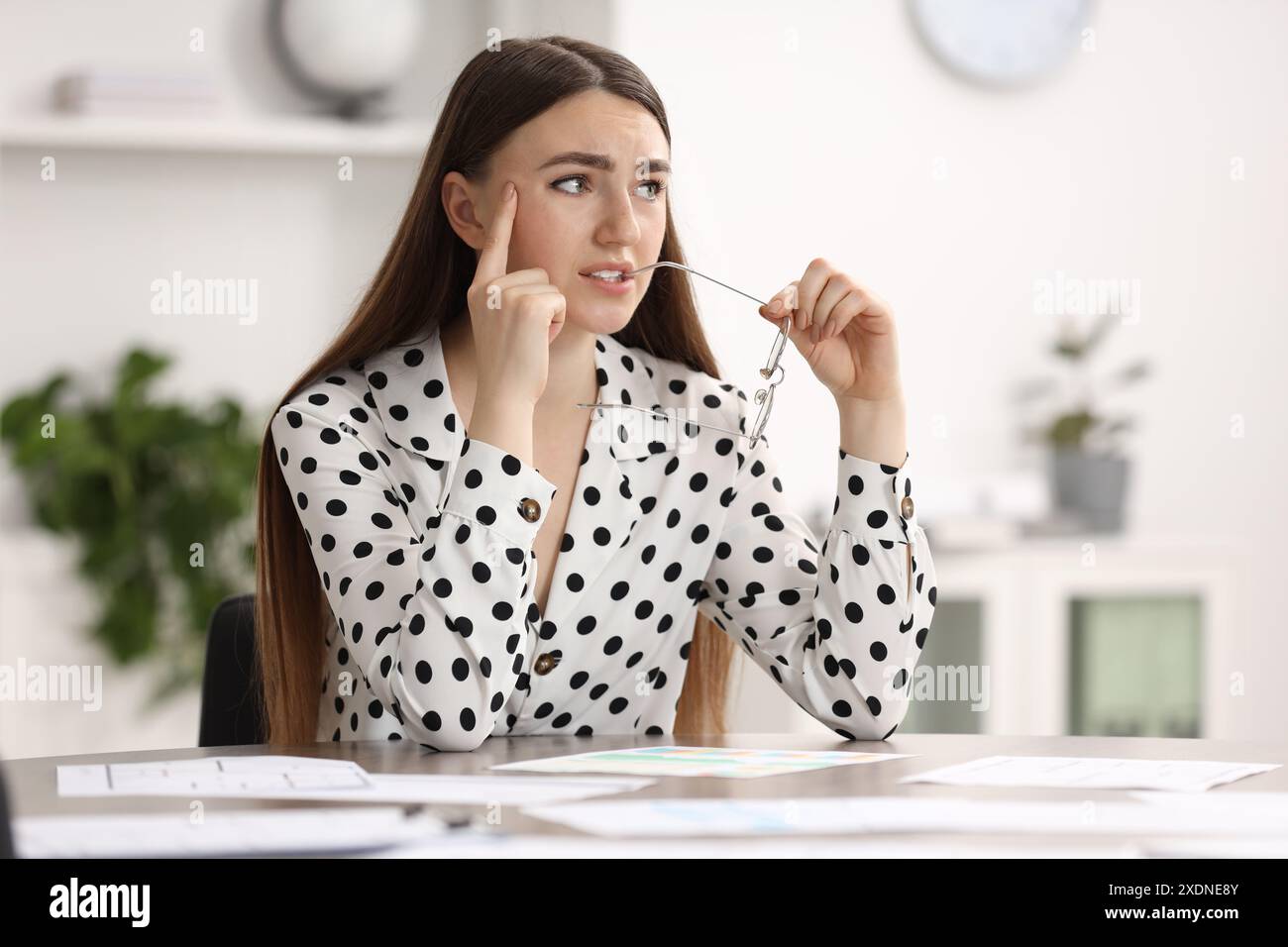 Embarrassed woman with glasses at table in office Stock Photo - Alamy