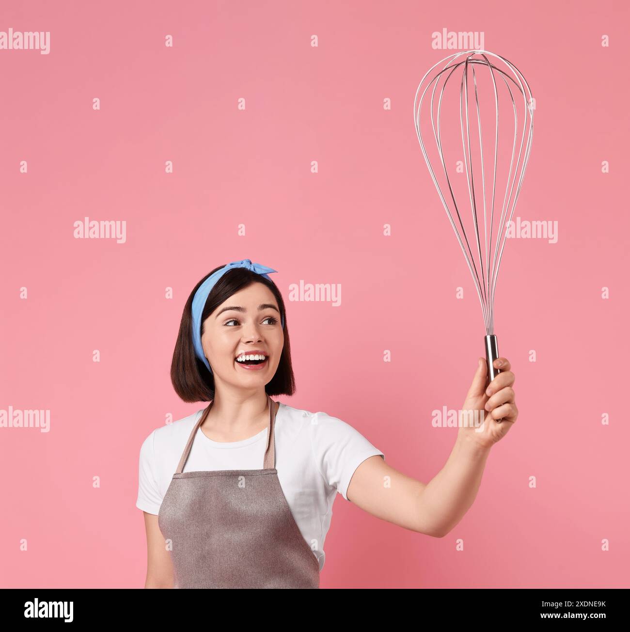 Happy pastry chef with big whisk on pink background Stock Photo - Alamy