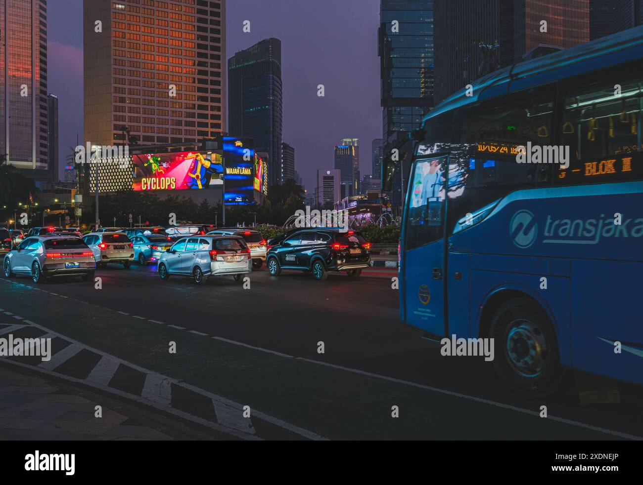 Jakarta, Indonesia - May 10th, 2024. A blue Transjakarta bus travels down a busy street in ...