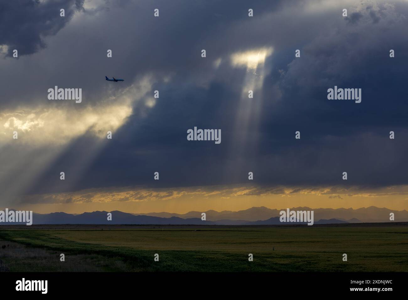 An airplane flying in the stormy sky above the Colorado prairies with ...