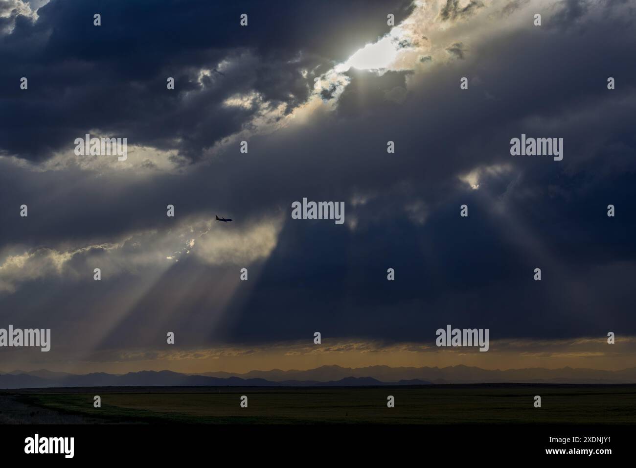 An airplane flying in the stormy sky above the Colorado prairies with ...