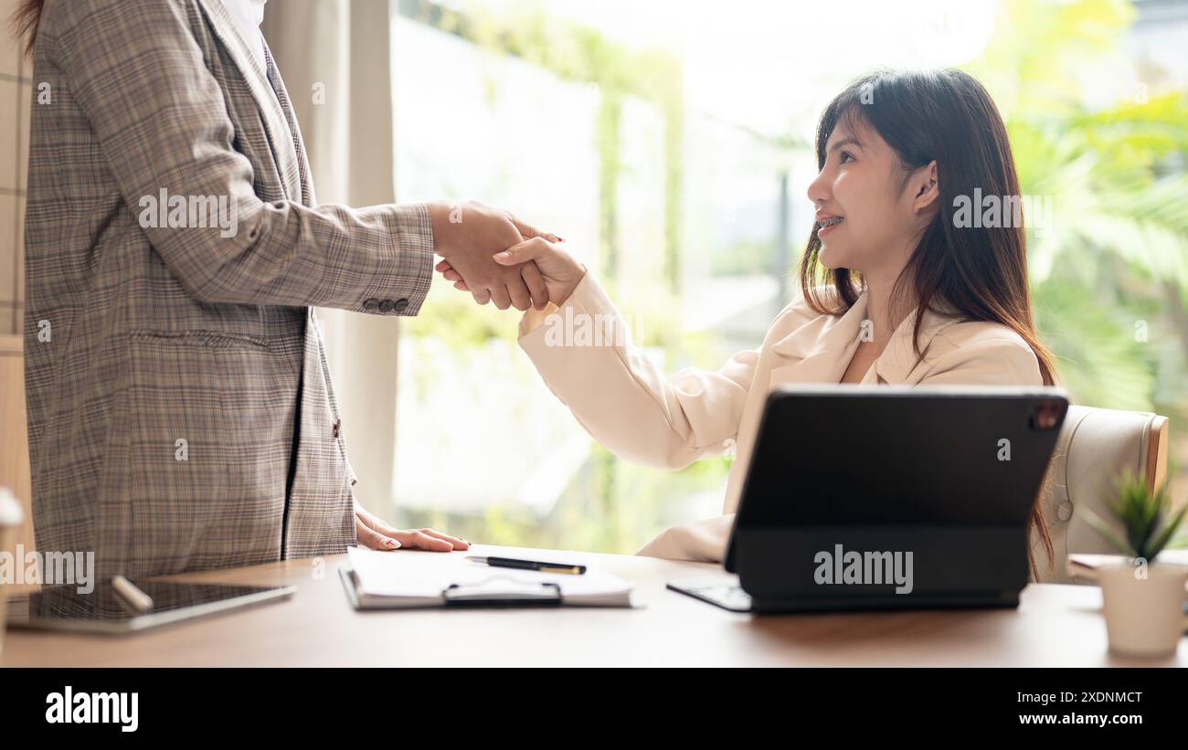 An Asian businesswoman or female office worker is shaking hands with ...