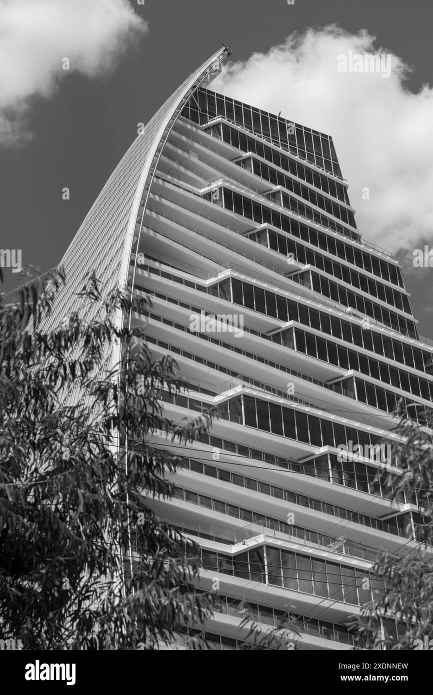 This black and white photograph features a modern, sail-like curved ...