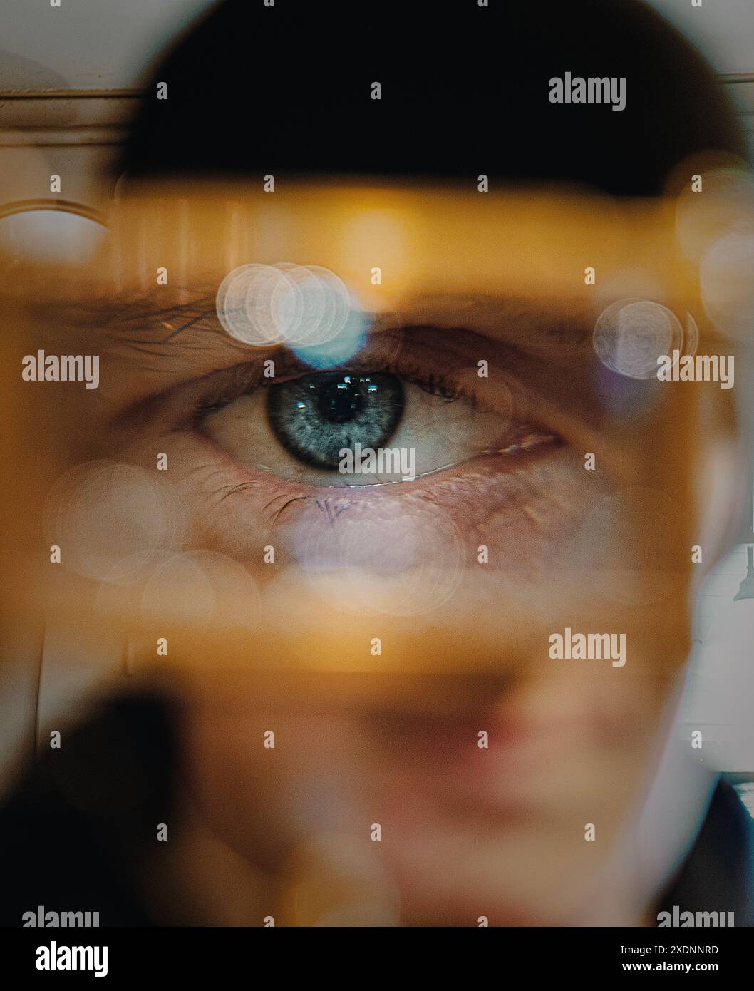 The man's blue eye stares into the camera through a magnifying glass ...