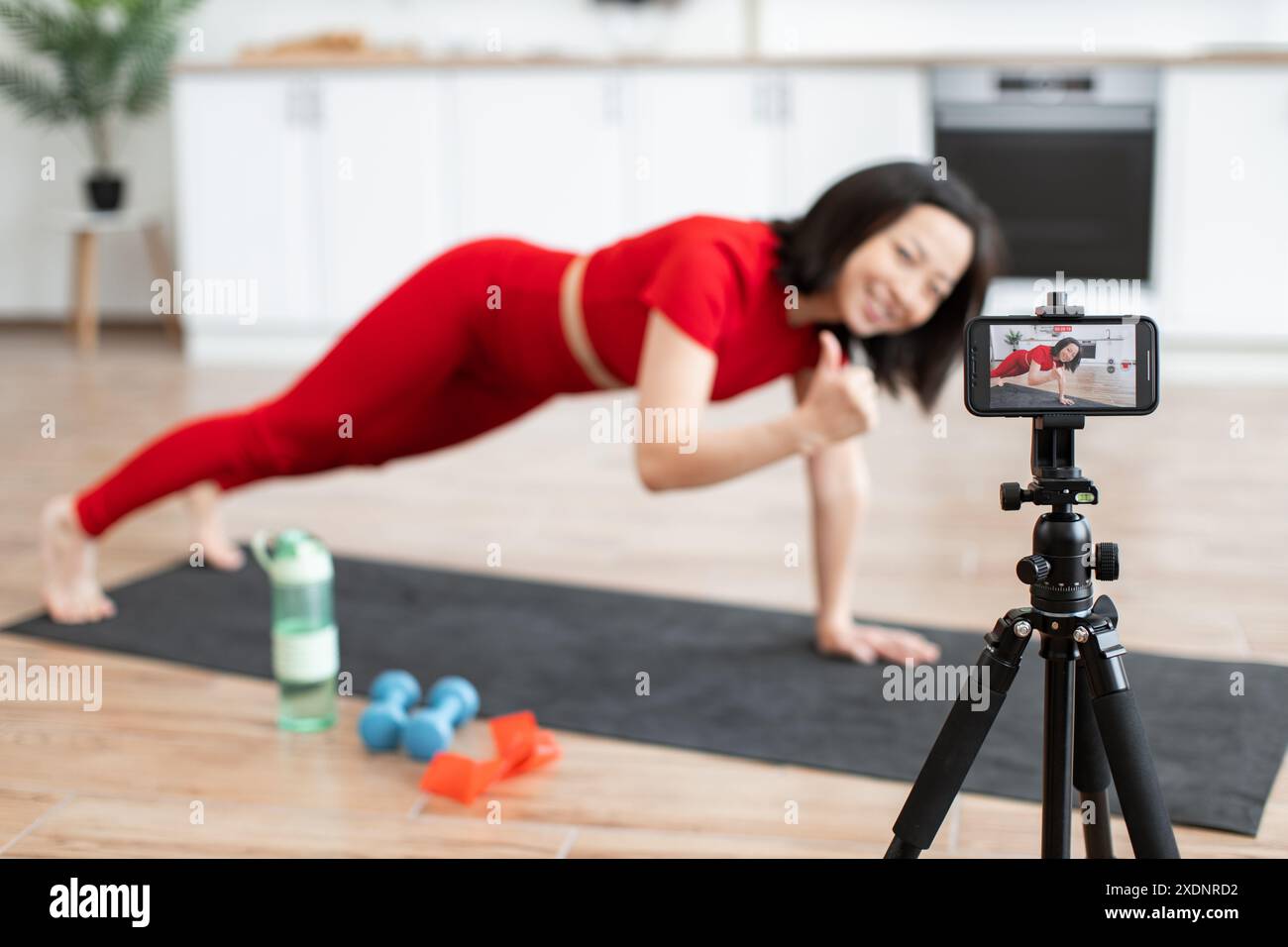 Woman recording fitness video at home giving thumbs up Stock Photo - Alamy