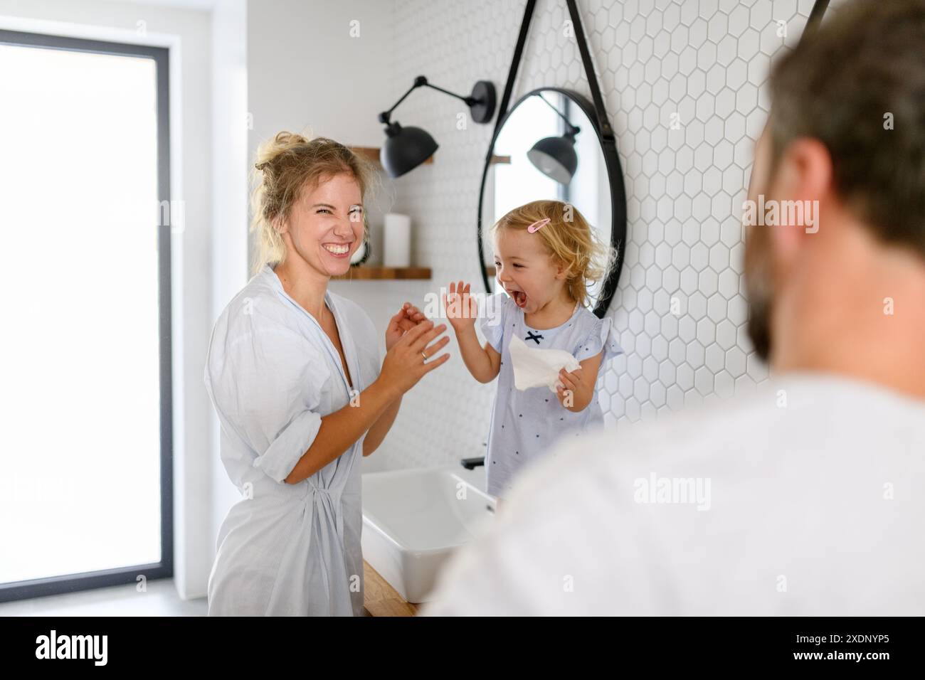 Parents and daughter having morning bathroom routine, brushing teeth ...