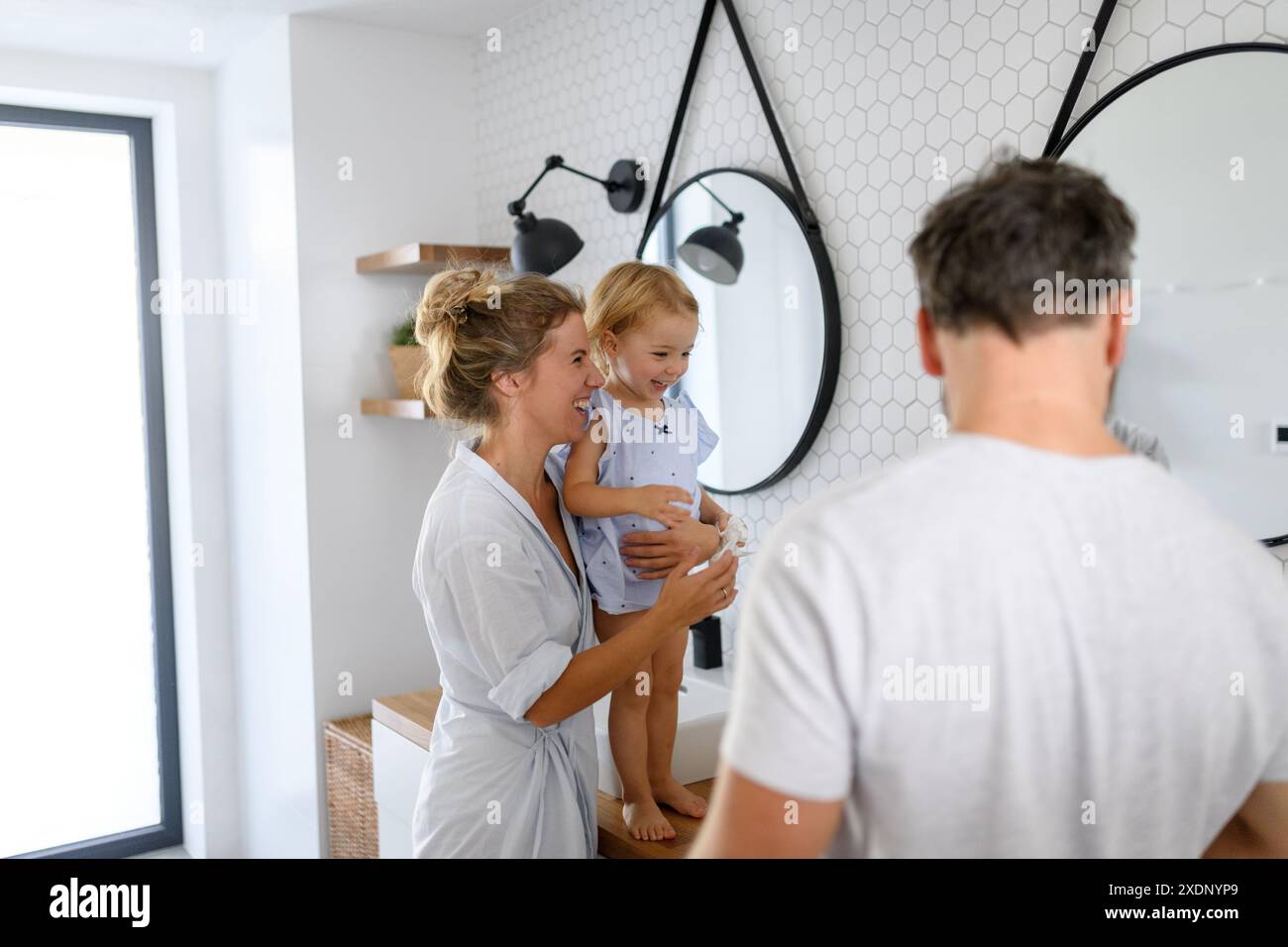 Parents and daughter having morning bathroom routine, brushing teeth ...
