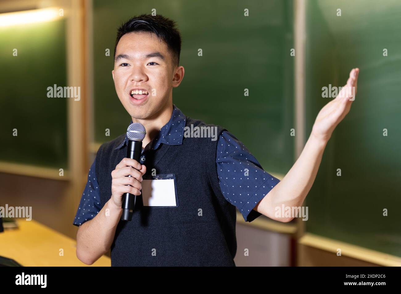 A young teenaged student is giving a presentation, gesturing while ...