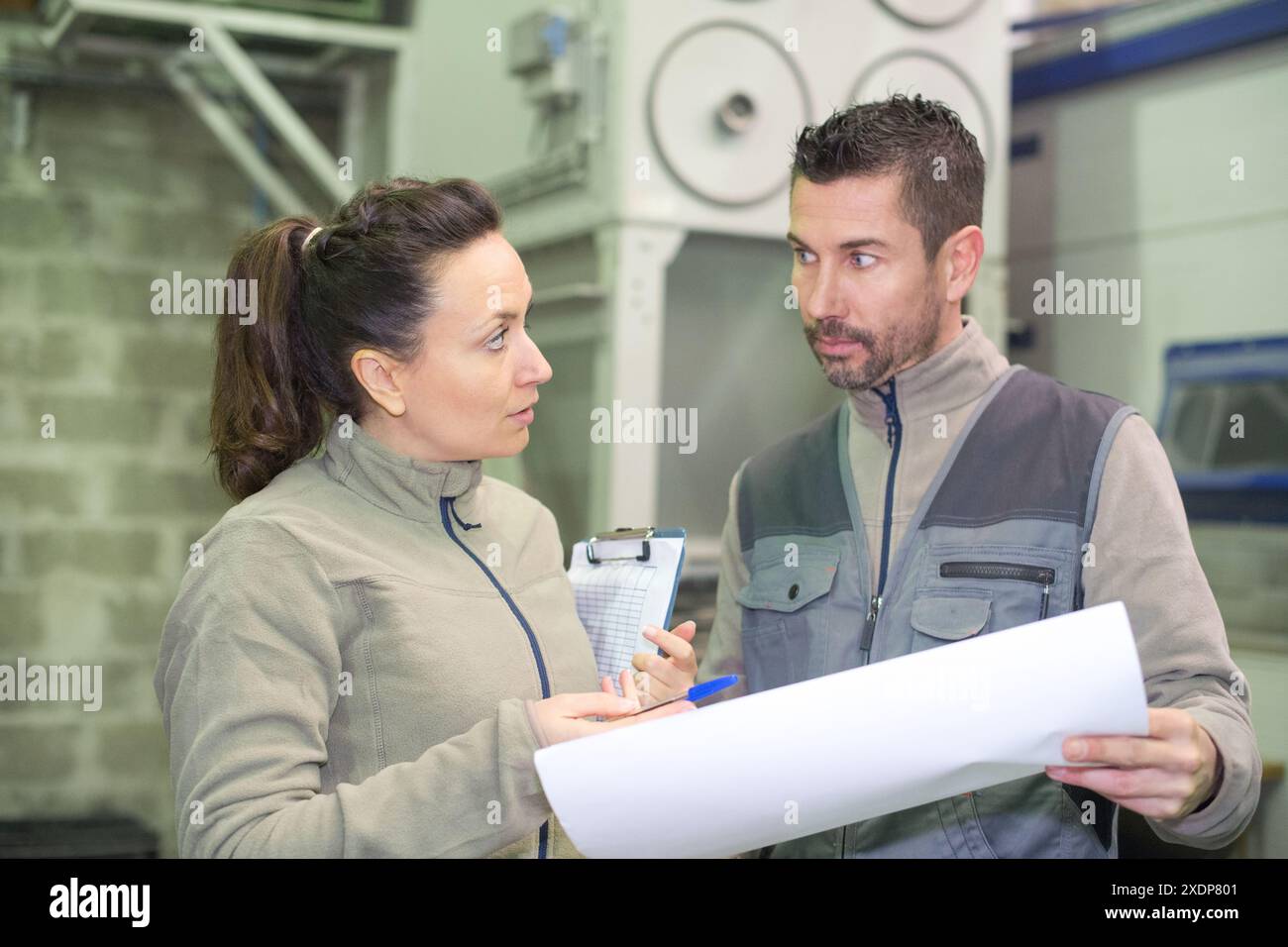 colleagues in discussion in factory looking at paperwork Stock Photo ...