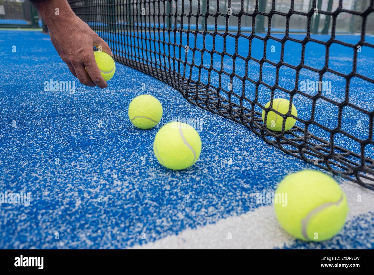 a man's hand catching a ball by the net of a paddle tennis court Stock ...