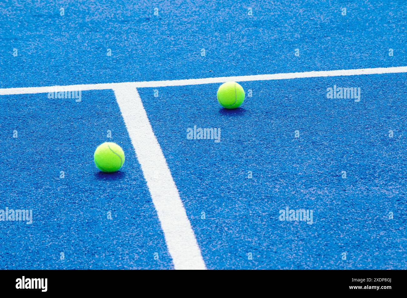 two balls on the surface of a blue paddle tennis court, racket sports ...