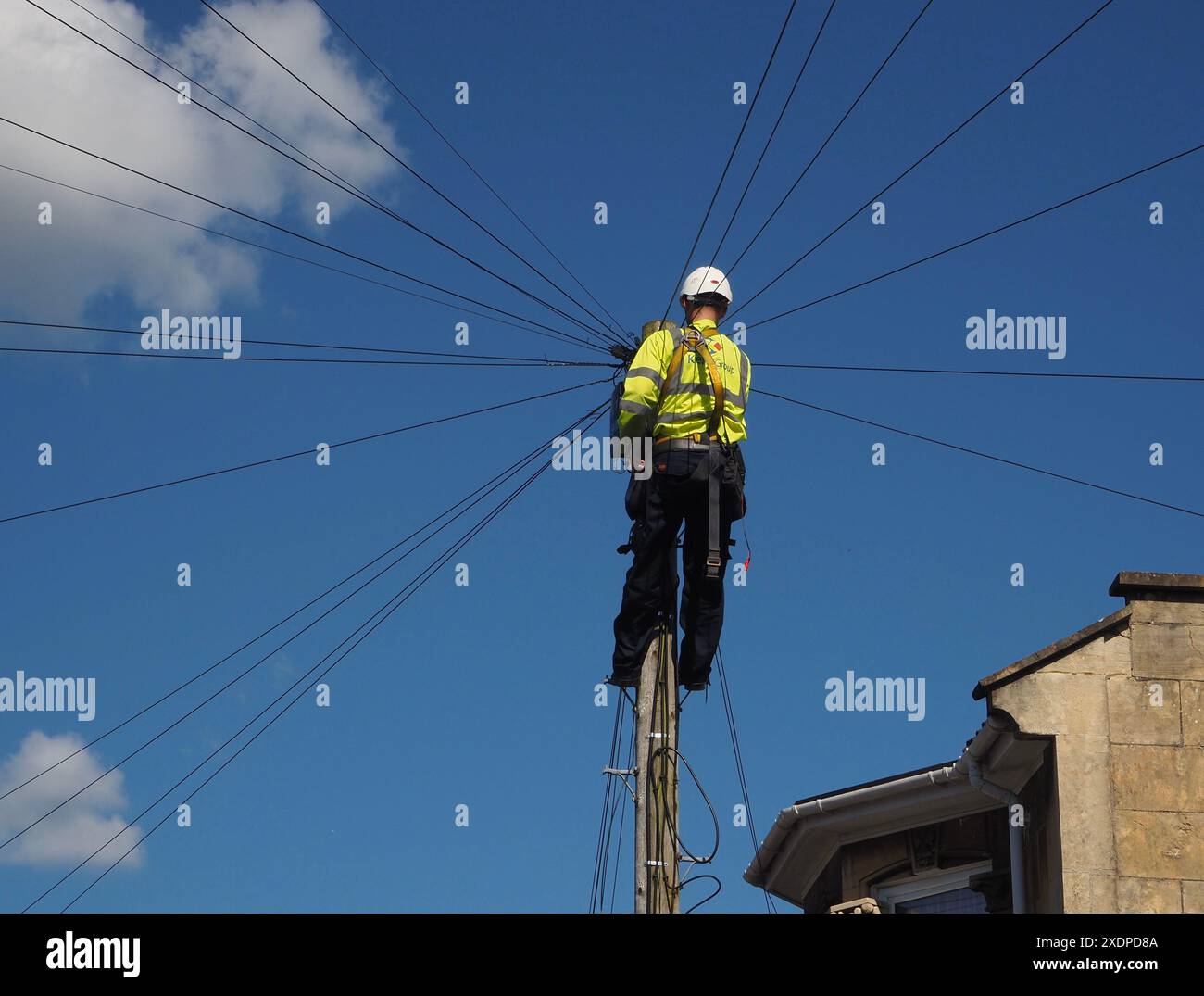 Telecommunications engineer in hi-viz jacket working on cabling at top ...