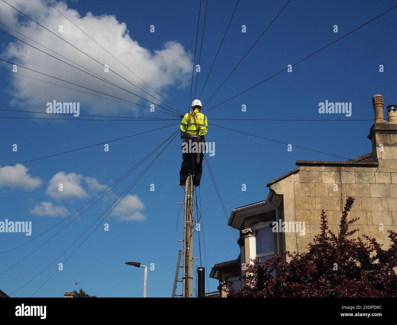 Telecommunications engineer in hi-viz jacket working on cabling at top ...