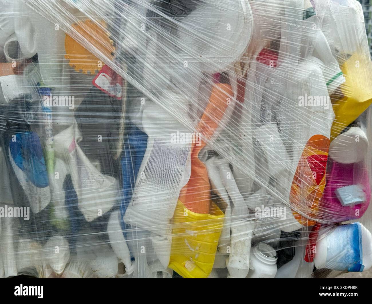 A tightly packed bale of mixed plastic containers wrapped in clear ...