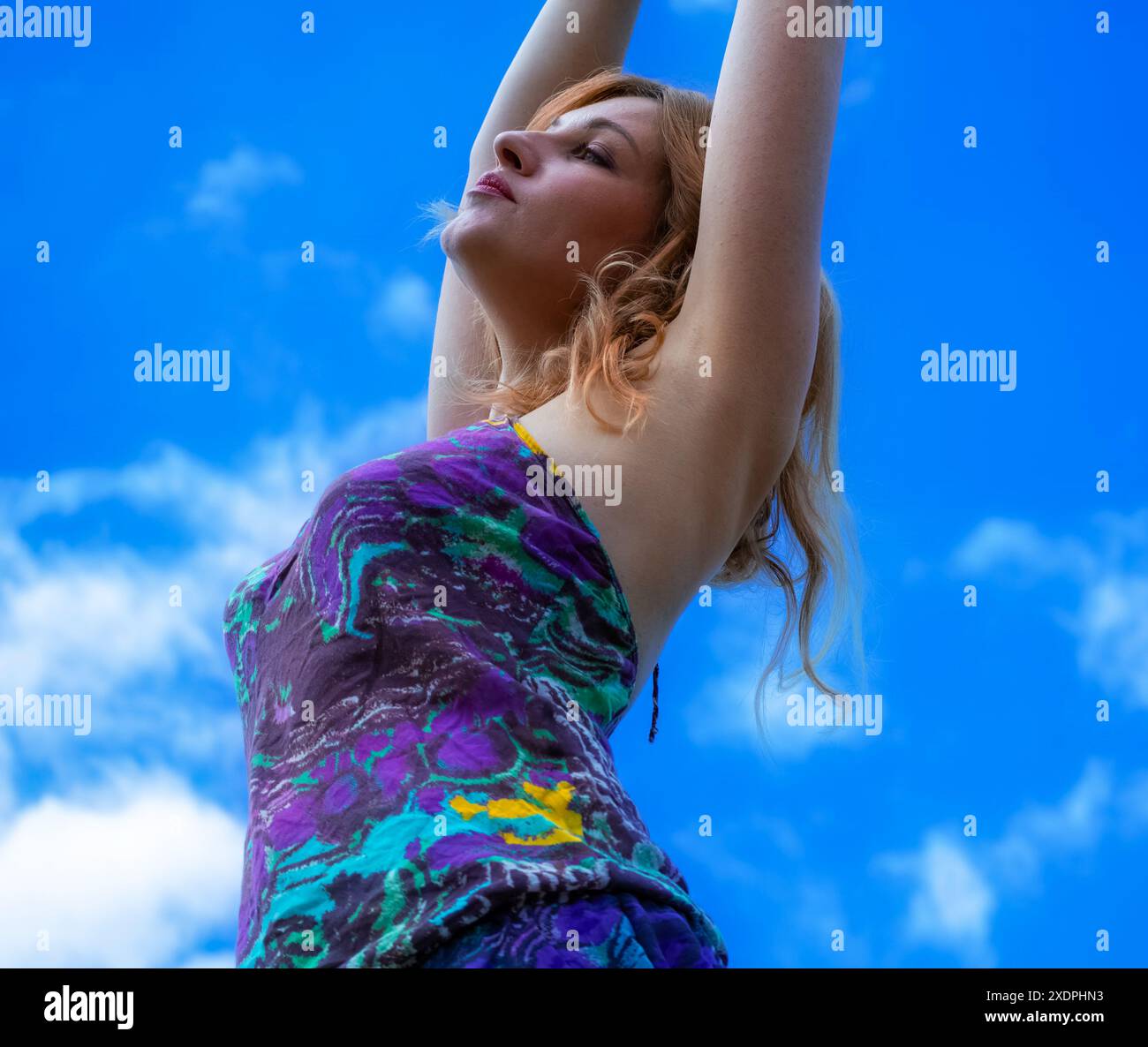 Woman in Floral Dress Reaching Upwards Against a Blue Sky Stock Photo ...