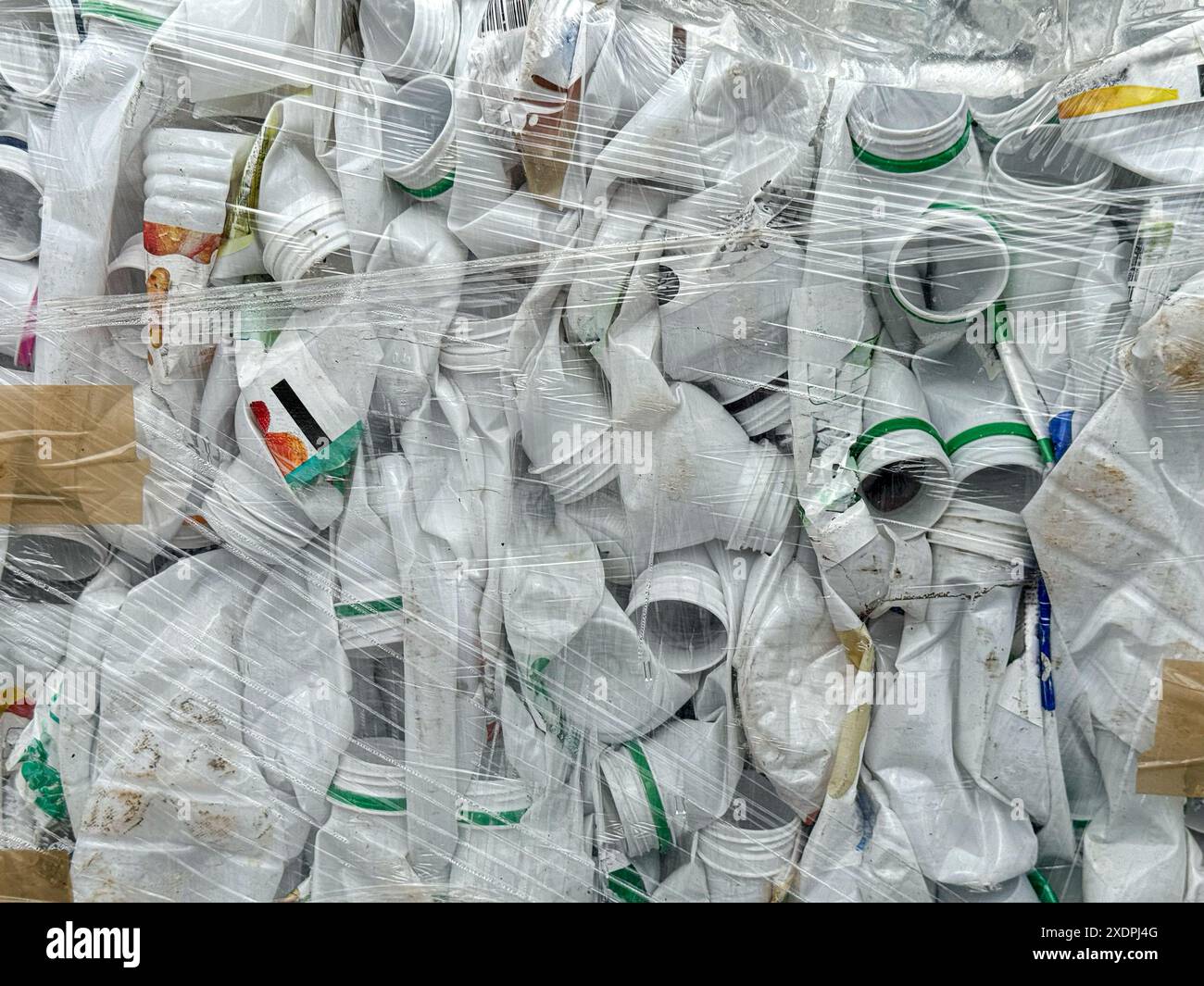 A bale of compressed white plastic containers wrapped in clear plastic ...