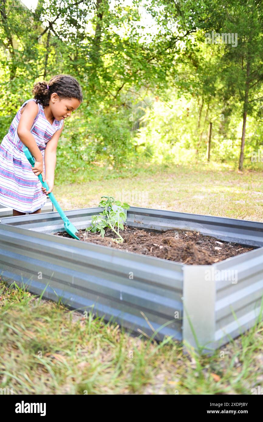 Girl digging in a garden bed, planting a seedling outdoors Stock Photo ...