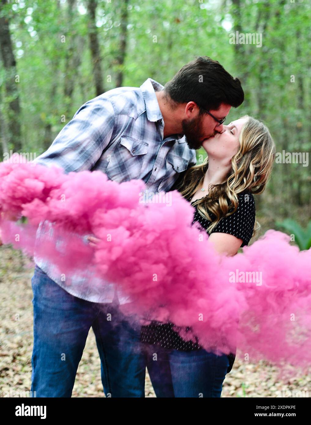 Couple kissing with pink smoke gender reveal in a forest backdr Stock ...