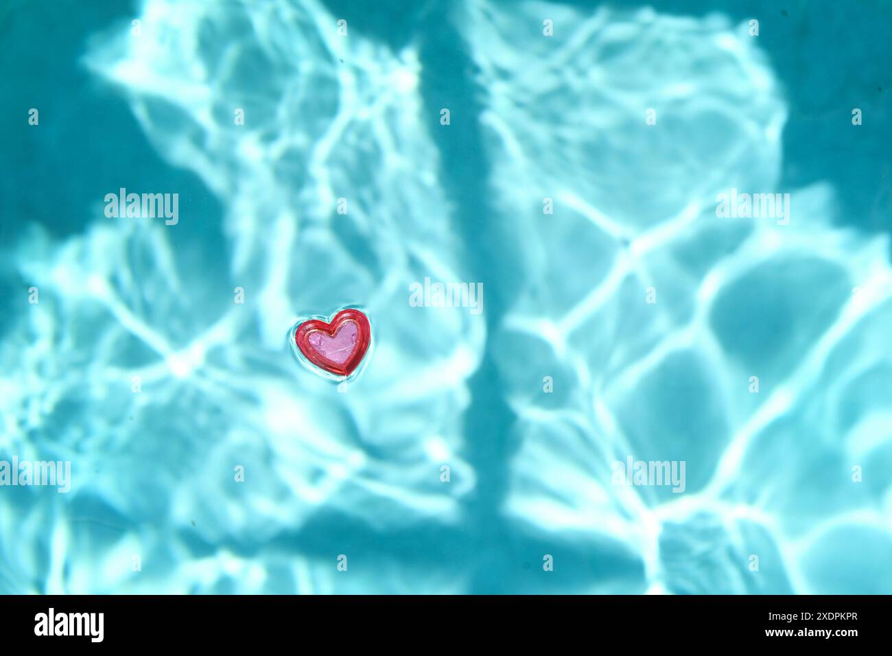 Red heart-shaped object floating in clear blue water Stock Photo - Alamy