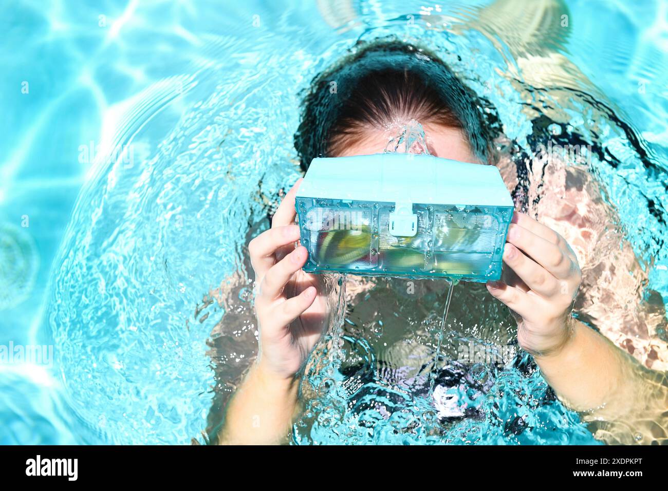Person holding a blue treasure chest underwater in a pool Stock Photo ...