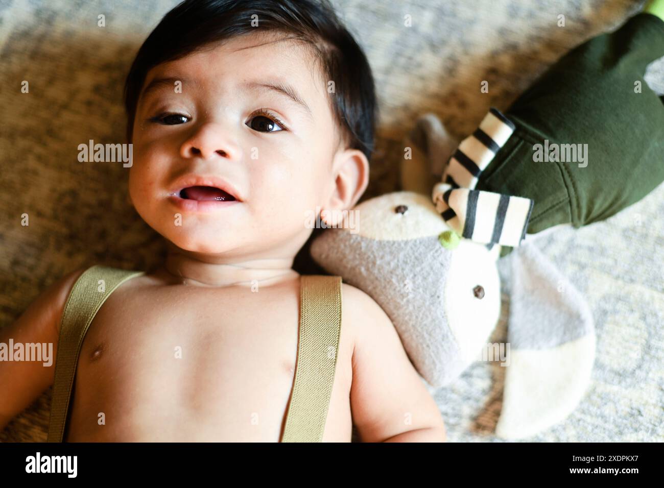 Baby lying on a soft surface with a stuffed toy beside them Stock Photo ...