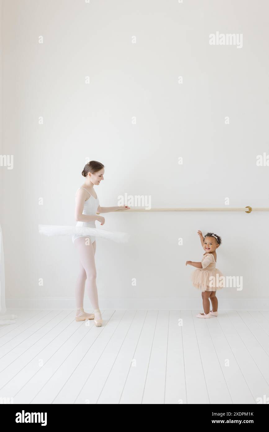 baby ballerina points to ballet barre in white studio Stock Photo - Alamy