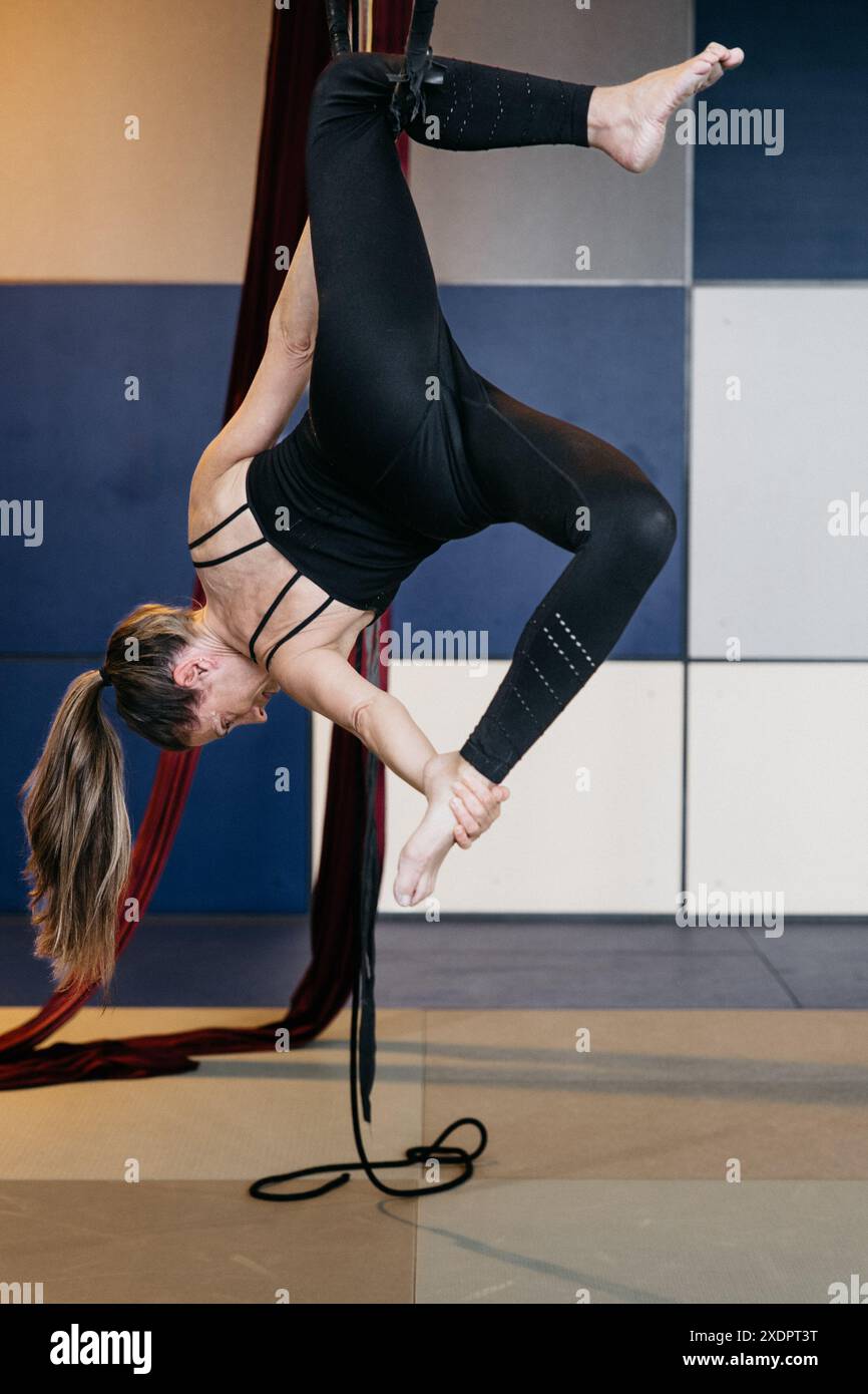 Athletic woman executing an acrobatic exercise on an aerial hoop during ...