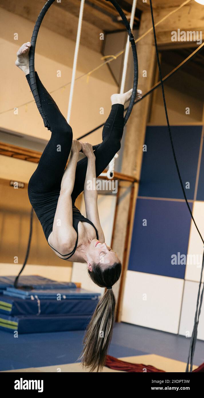 Woman performing an inverted exercise on an aerial hoop in a training ...