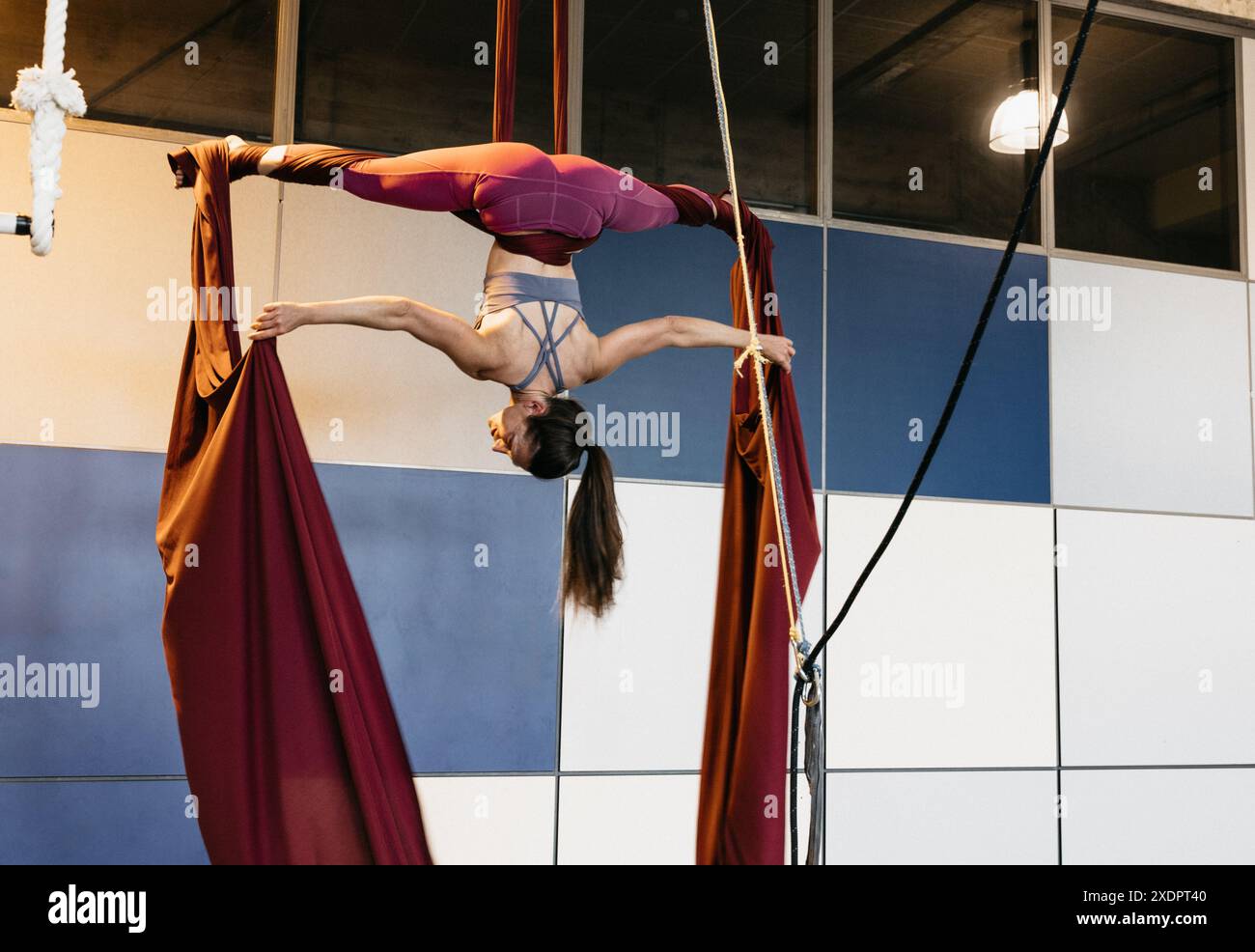 Woman performing an artistic figure on aerial silks in a studio ...