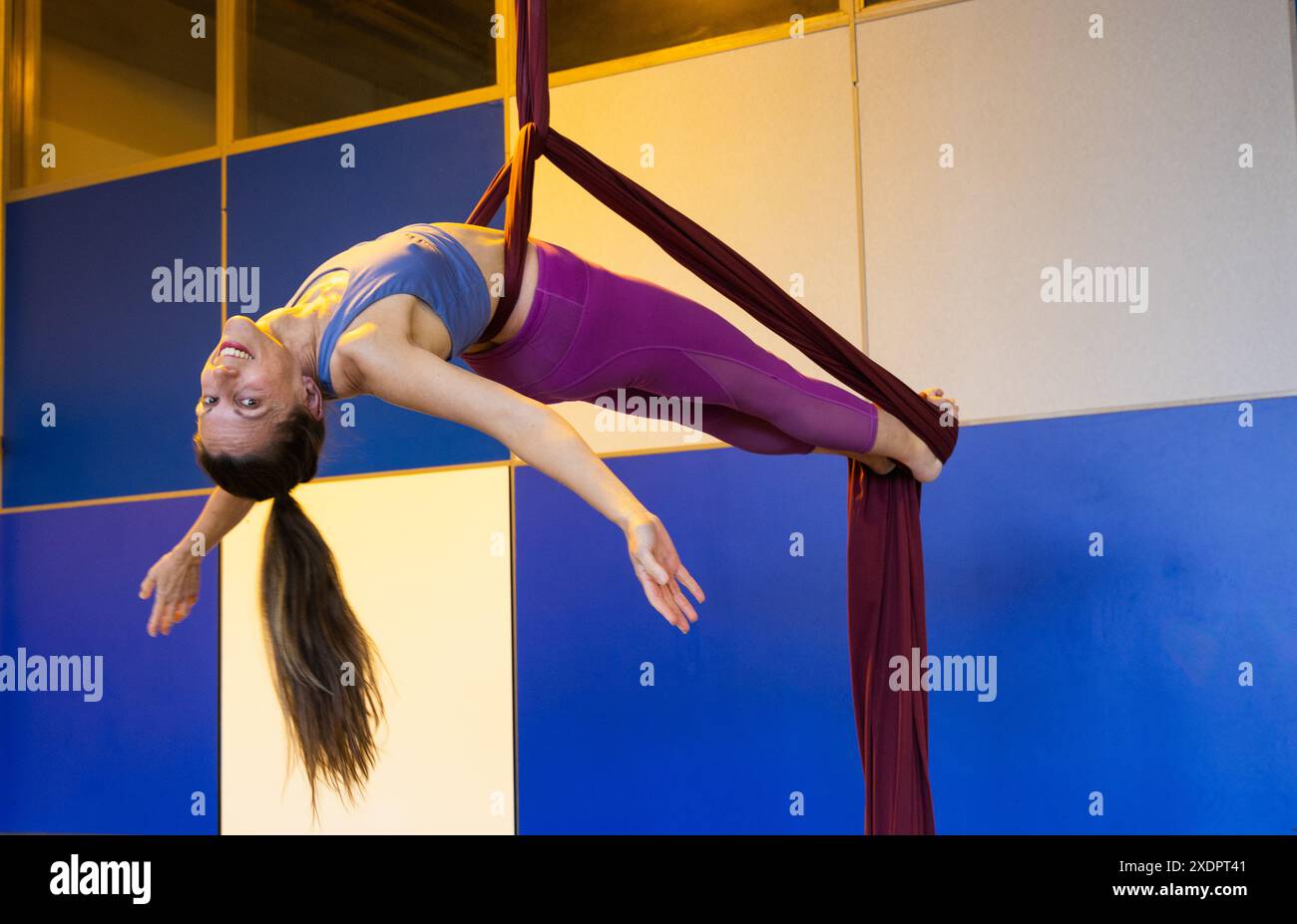 Athletic woman practicing a horizontal exercise on aerial silks in a ...