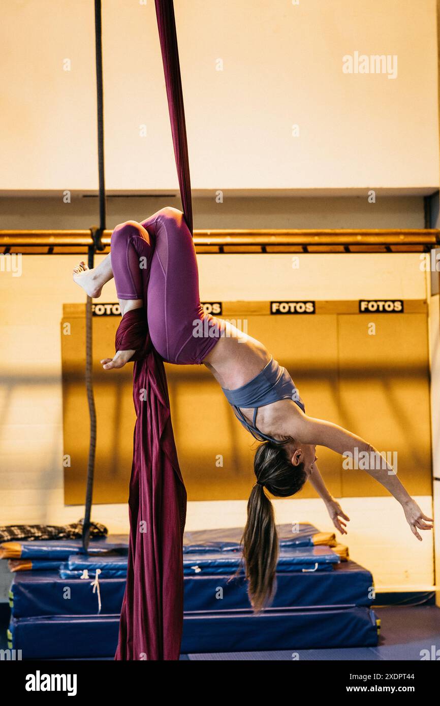 Woman performing an inverted acrobatic pose with aerial silks in a ...
