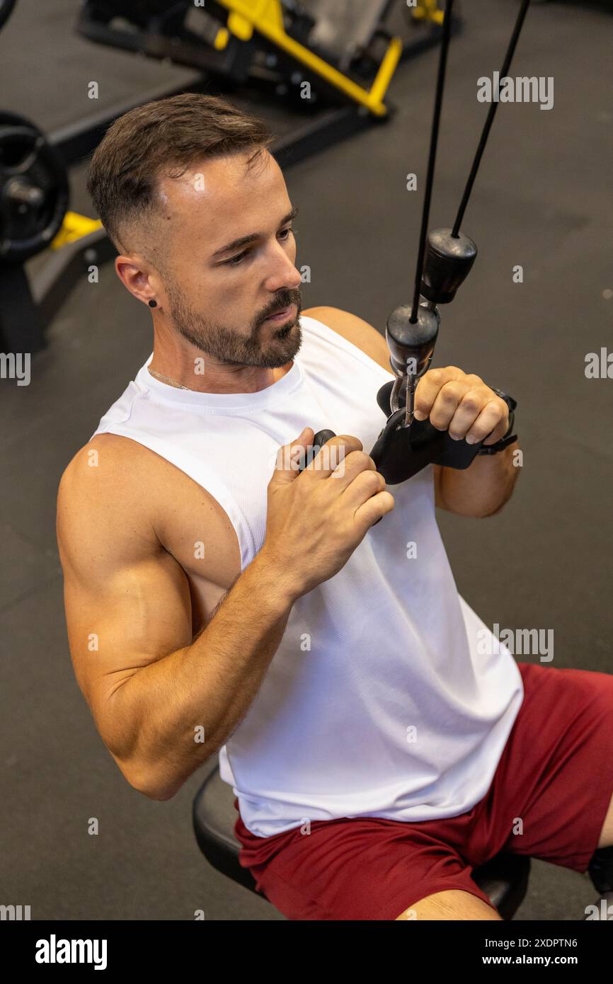 Muscular man in the gym training back sitting on the bench Stock Photo ...