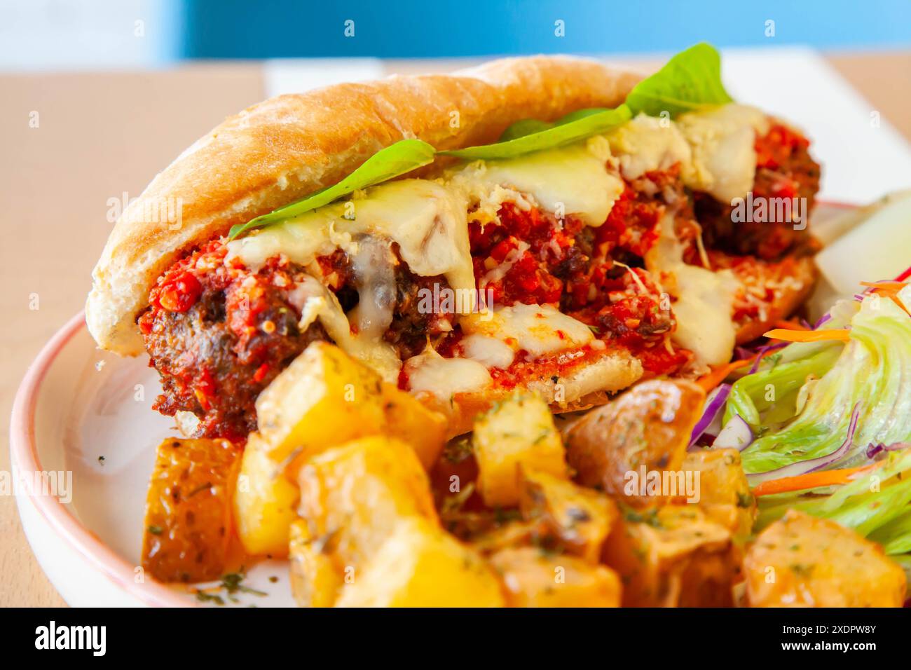 Meatball sub sandwich in baguette bread served in a cafe with sautéd ...