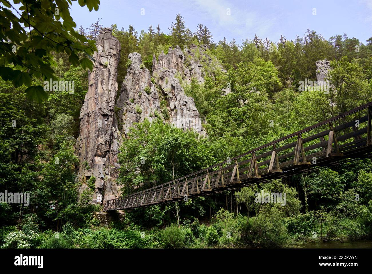 Wooden bridge is spanning a river, leading towards dramatic rock ...