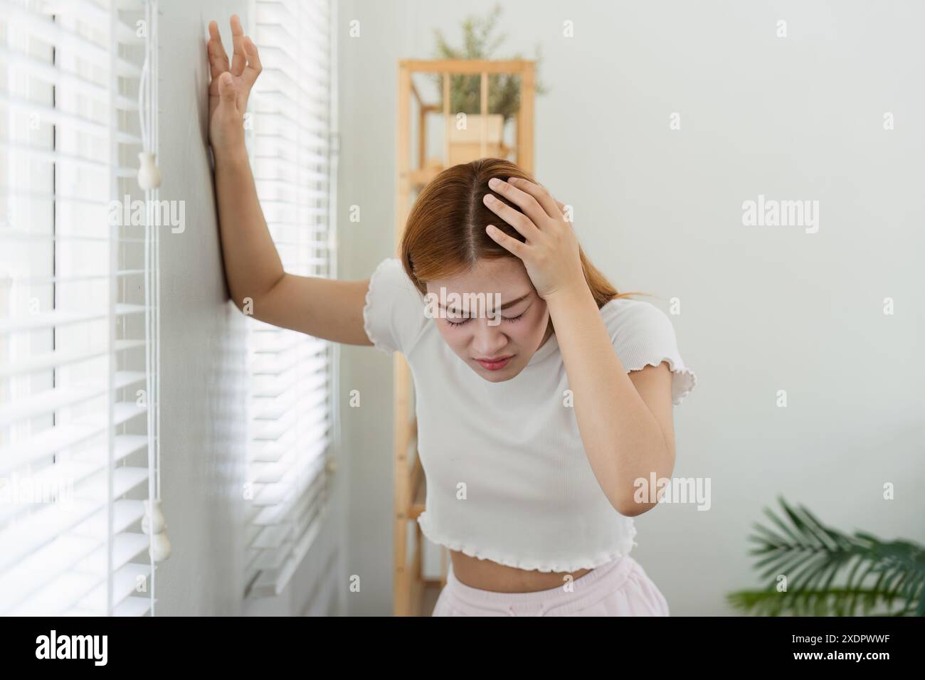 Young Woman Feeling Dizzy and Holding Her Head While Leaning Against a ...