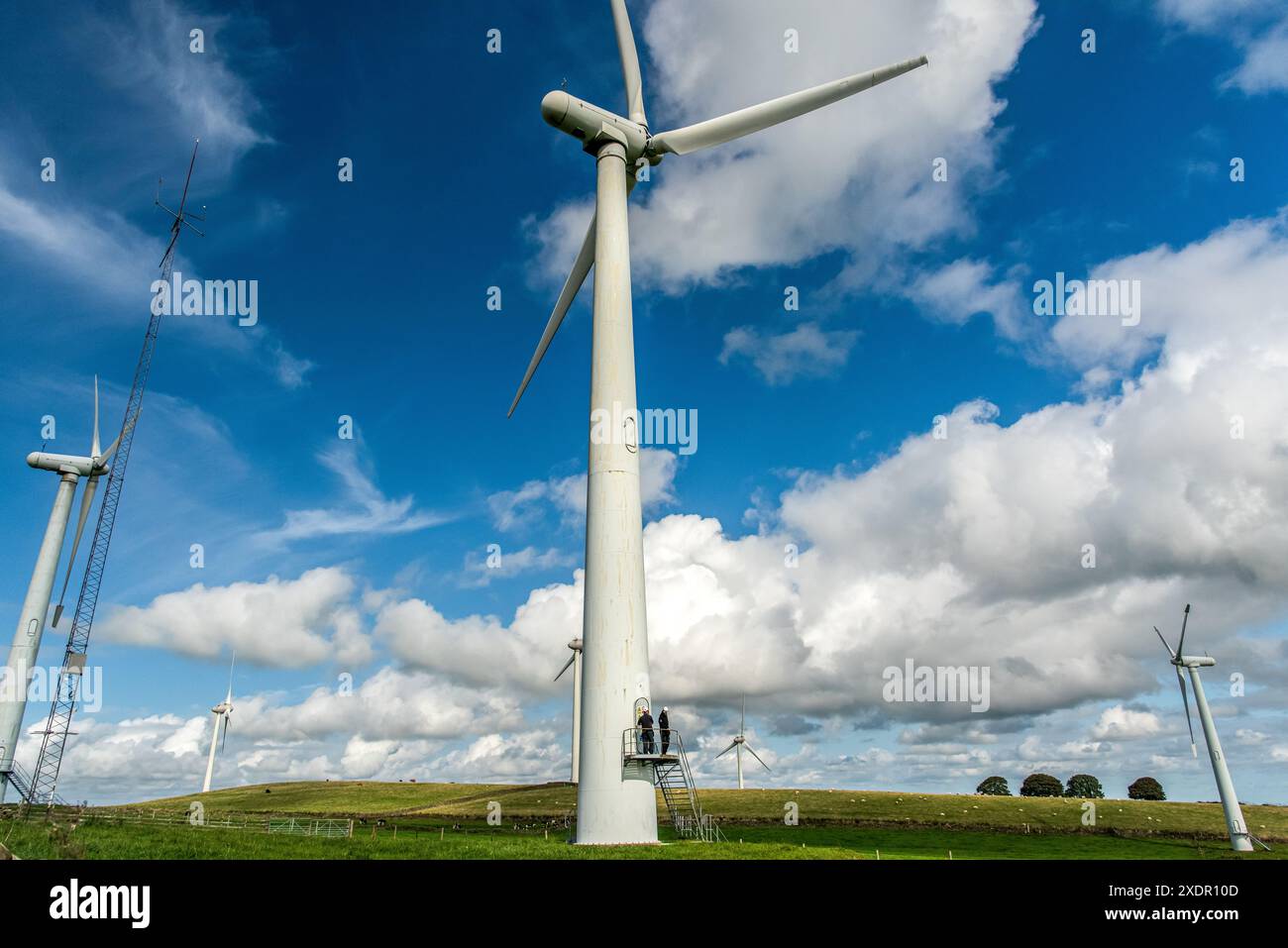 Low down view, looking up at a wind turbines, with two engineers ...