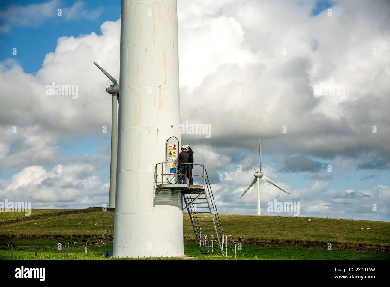 View of a wind turbine tower with two engineers standing on its ...