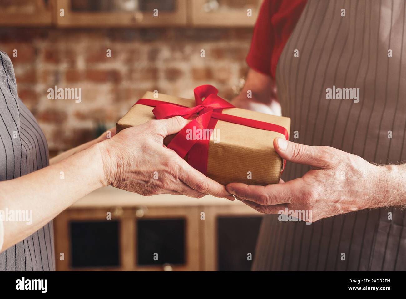 Person Giving Gift Wrapped in Brown Paper With Red Ribbon Stock Photo ...