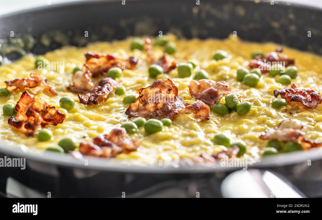 Saffron risotto with Parmesan cheese, peas and bacon in a pan Stock ...