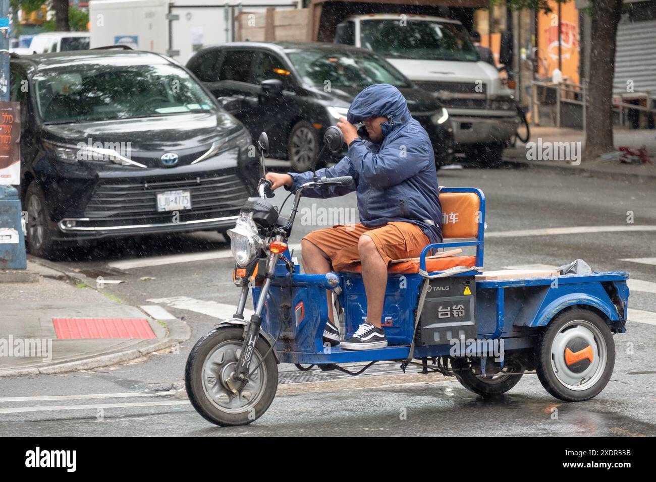 A delivery man makes his rounds in a light rain holding his raincoat ...