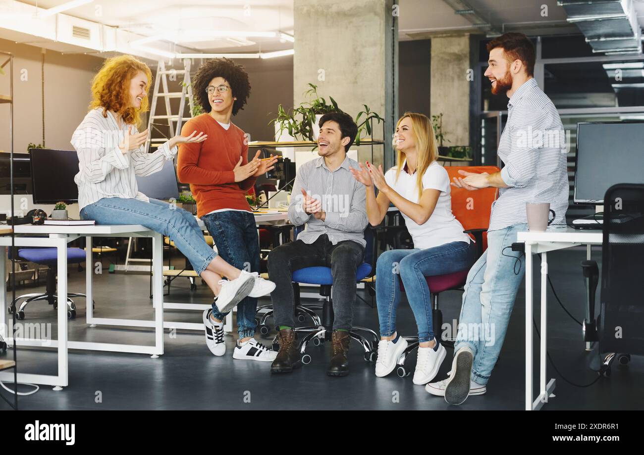 Cheerful coworkers welcoming new colleague in modern coworking Stock ...